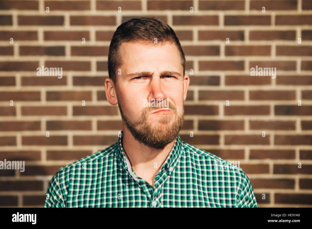 dissatisfied man looking at the camera on Brick wall background Stock ...