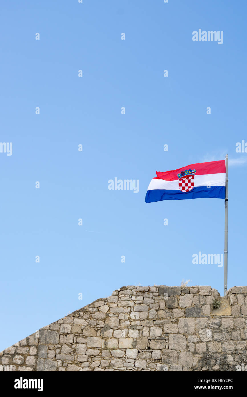 A Croatian flag flies in the wind above a historic fortress in Hvar ...