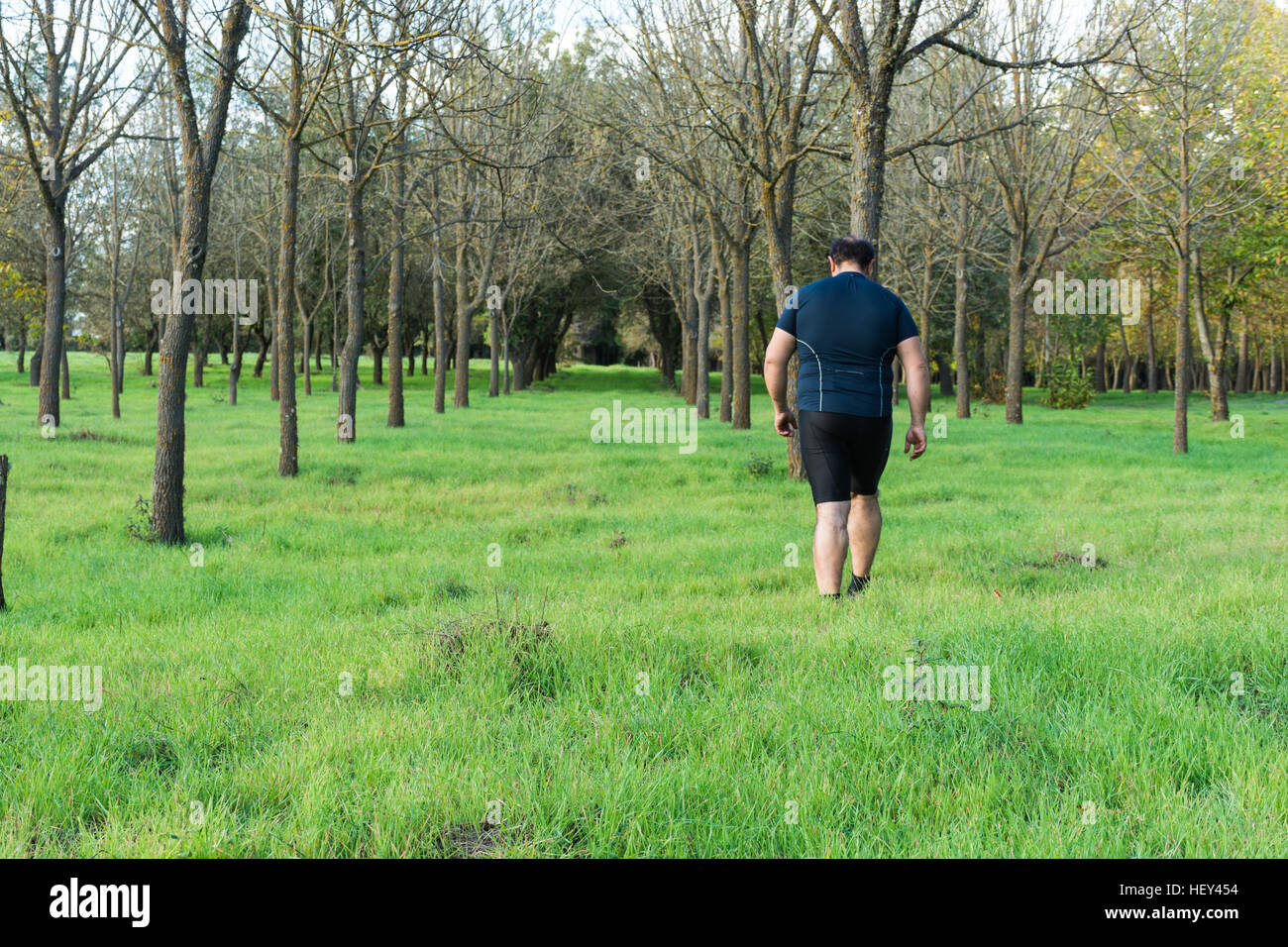 Big belly man jogging , exercising, doing cardio in the park , slightly ...