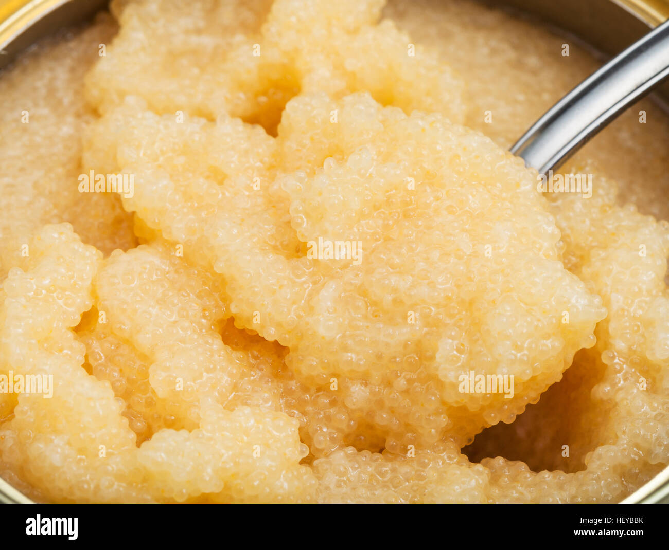 salty yellow caviar of capelin fish with spoon in can close up Stock ...