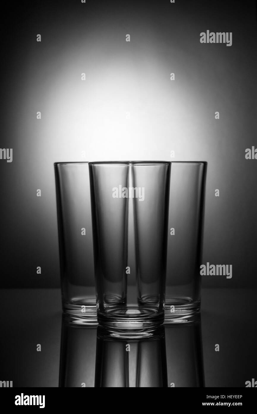 Three empty glasses on a blackand white background with reflection ...