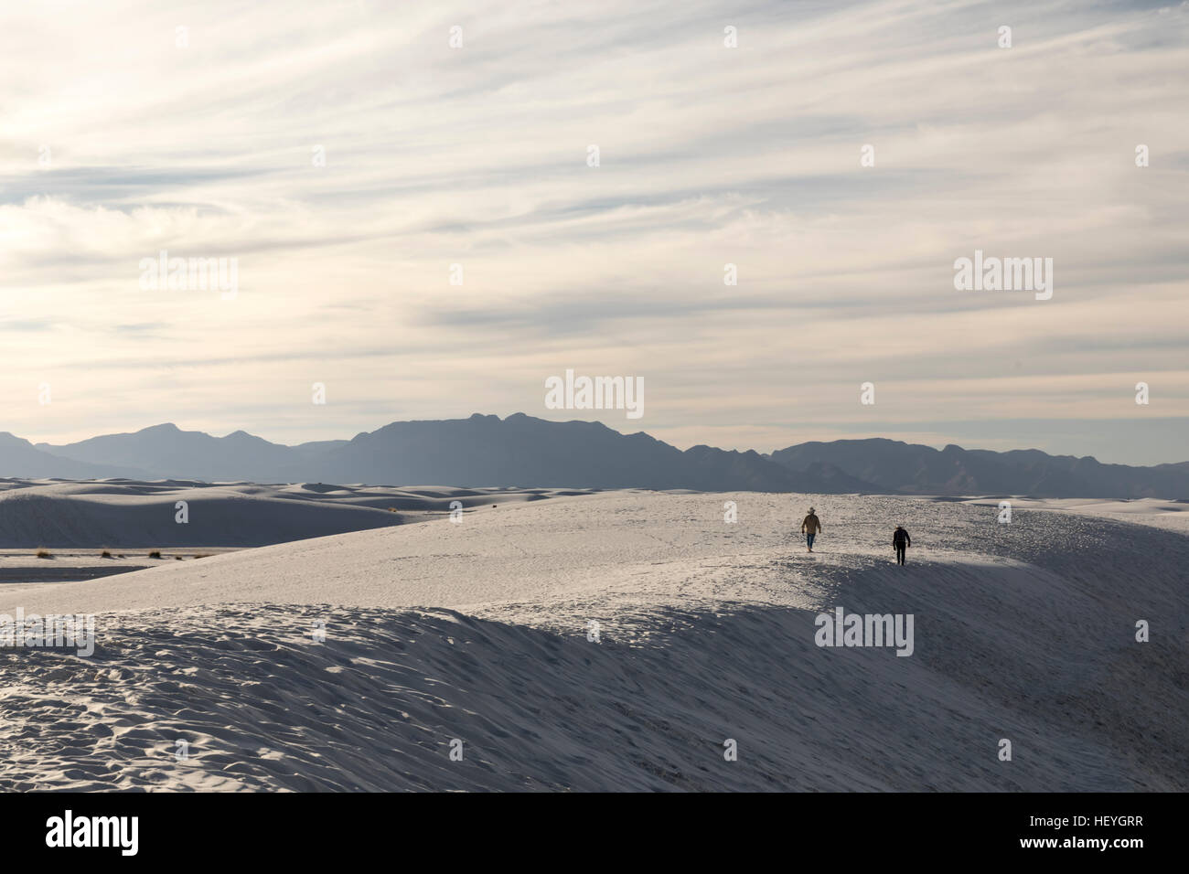 Two figures walk along crest of white gypsum sand dunes at White Sands ...