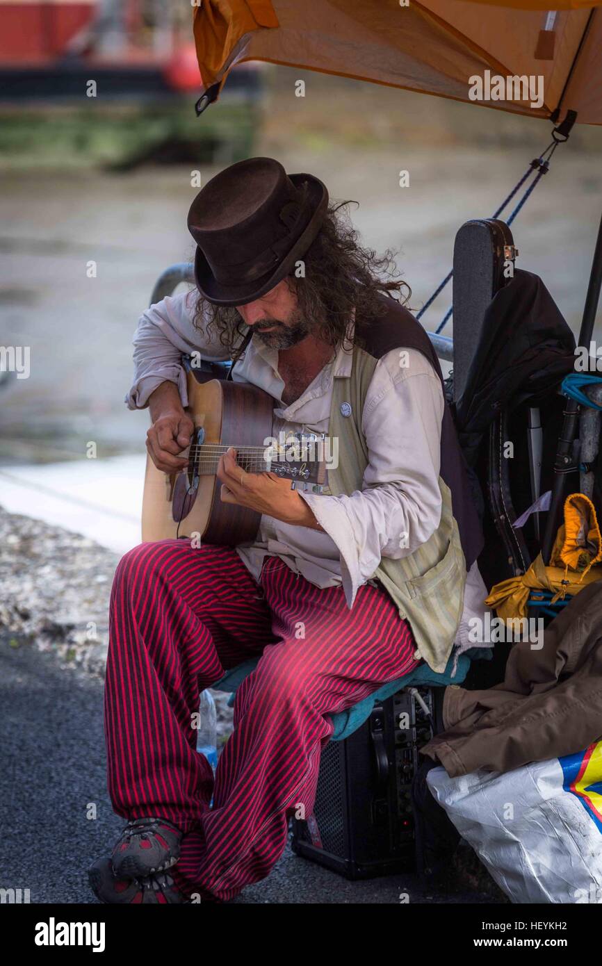 a musician busker playing acoustic guitar at Padstow Harbour in ...