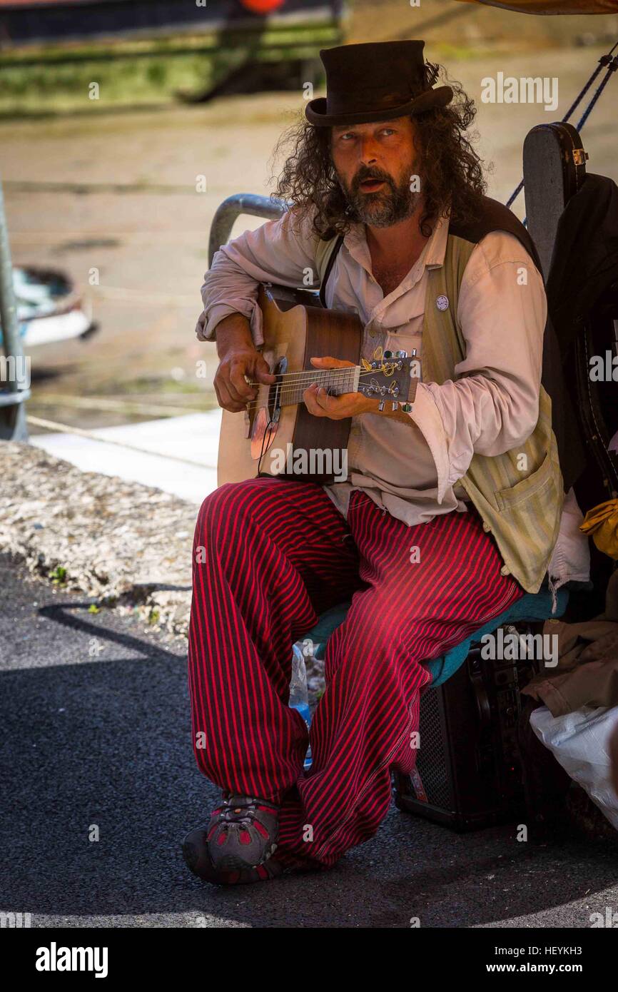 a musician busker playing acoustic guitar at Padstow Harbour in ...