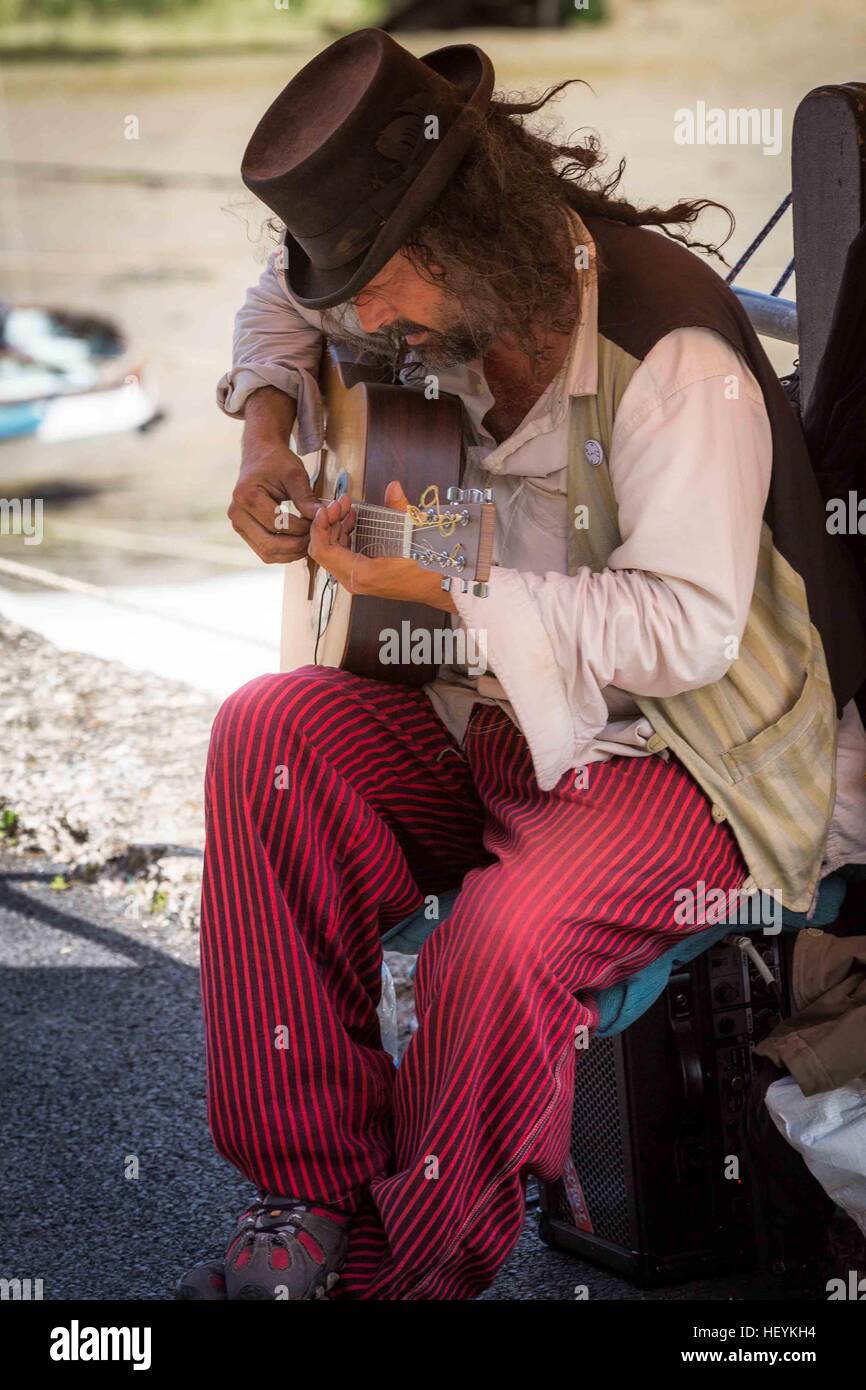 a musician busker playing acoustic guitar at Padstow Harbour in ...