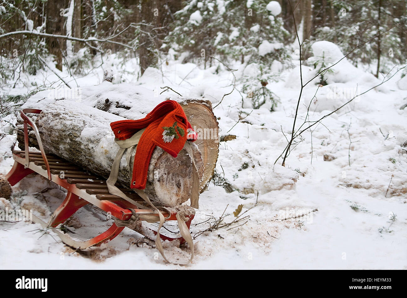 A timber laid on a children sled and red gloves on a top of it, snowy ...