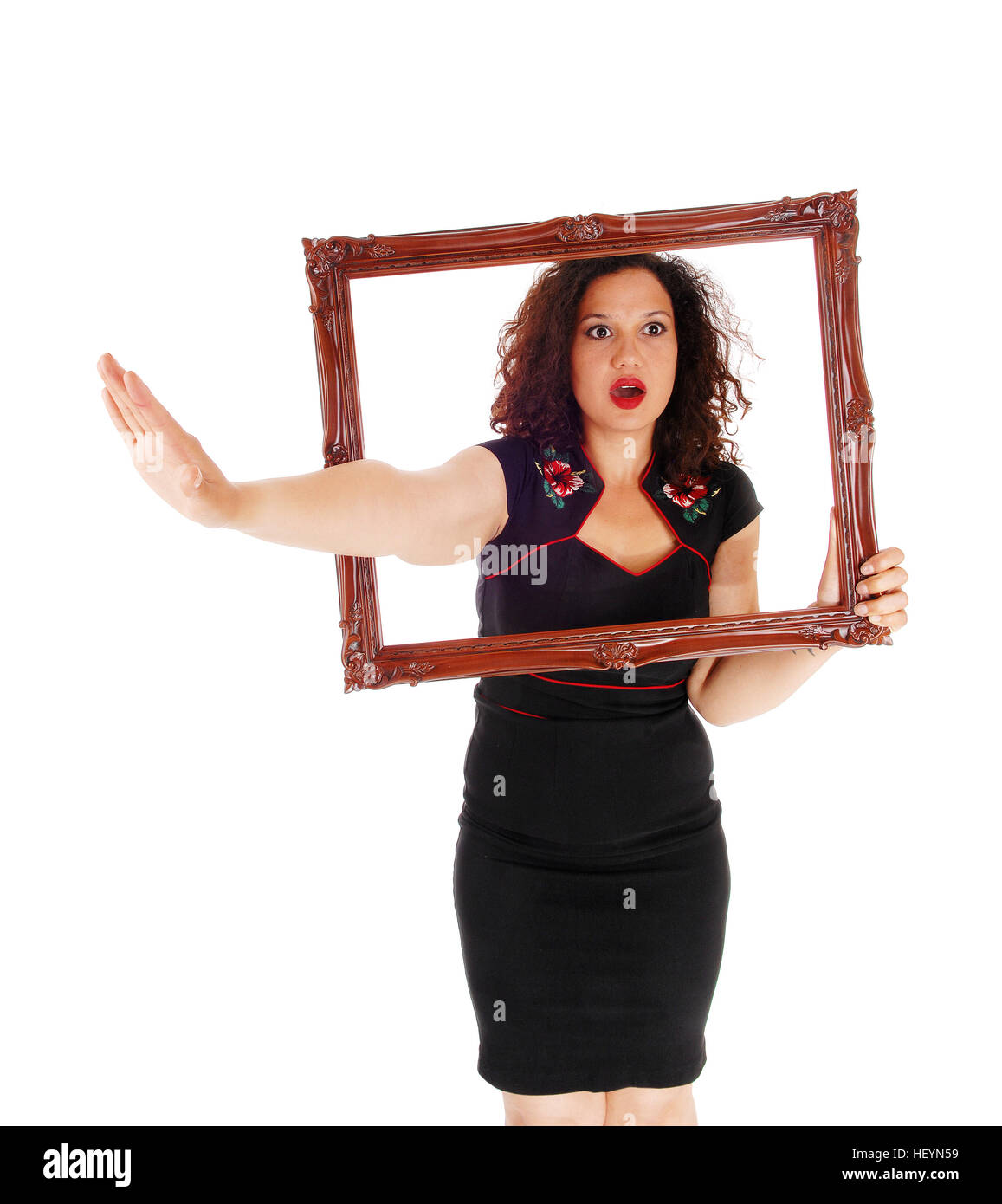 A angry woman looking trough a picture frame stretching one hand out ...