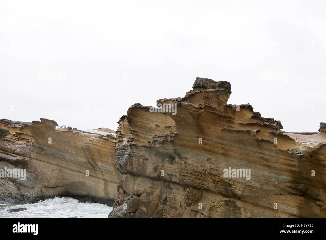 Rocky striated cliff face with white wash foam from ocean Stock Photo ...