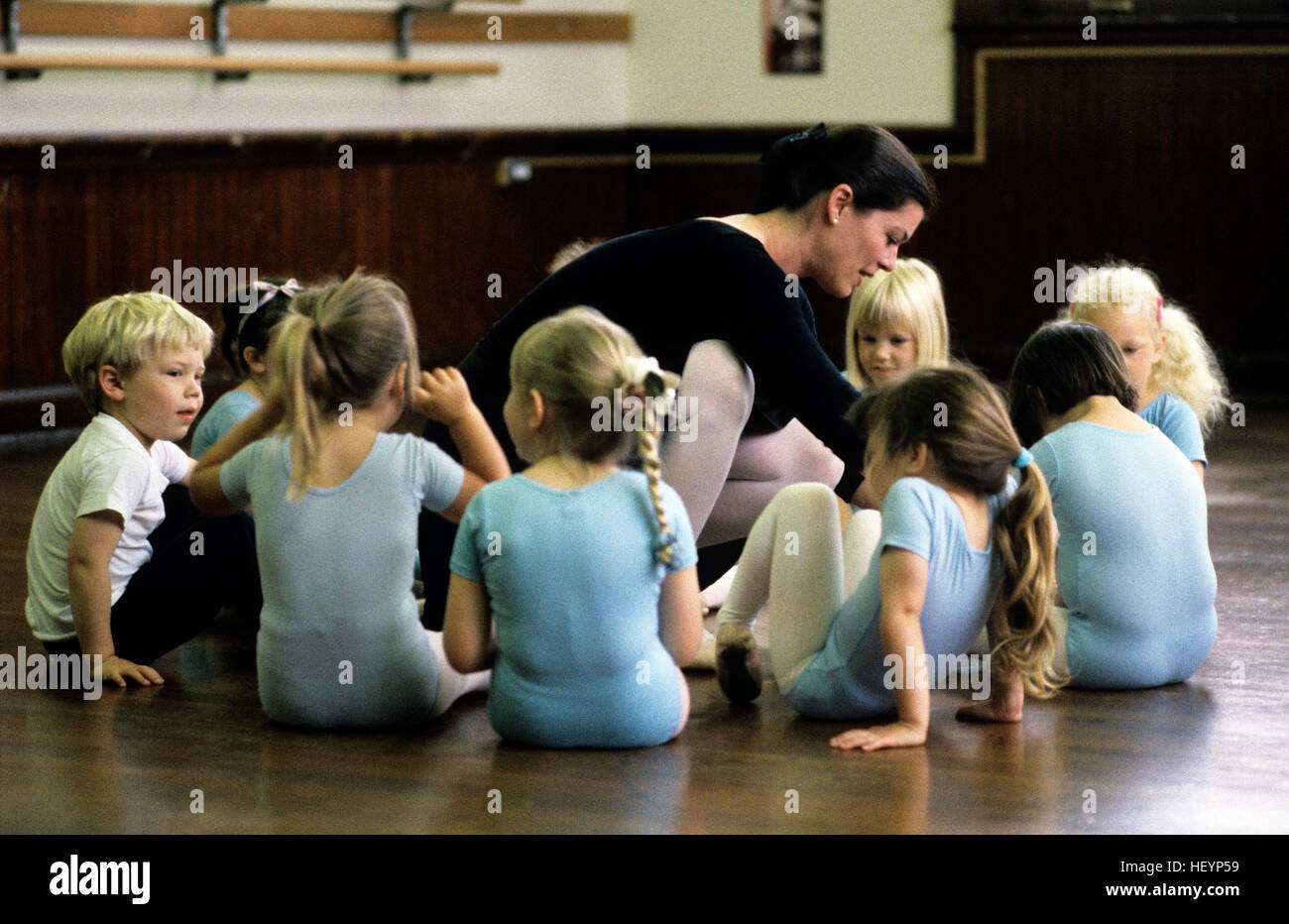 Young ballet dancers at a ballet class sitting while the instructor ...