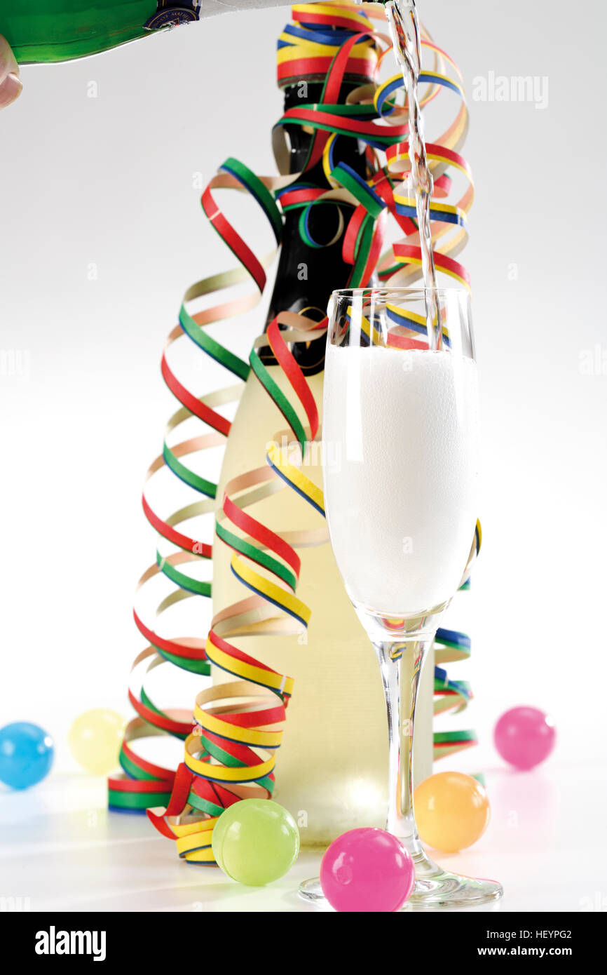Champagne poured into a glass, champagne bottle and paper streamers ...