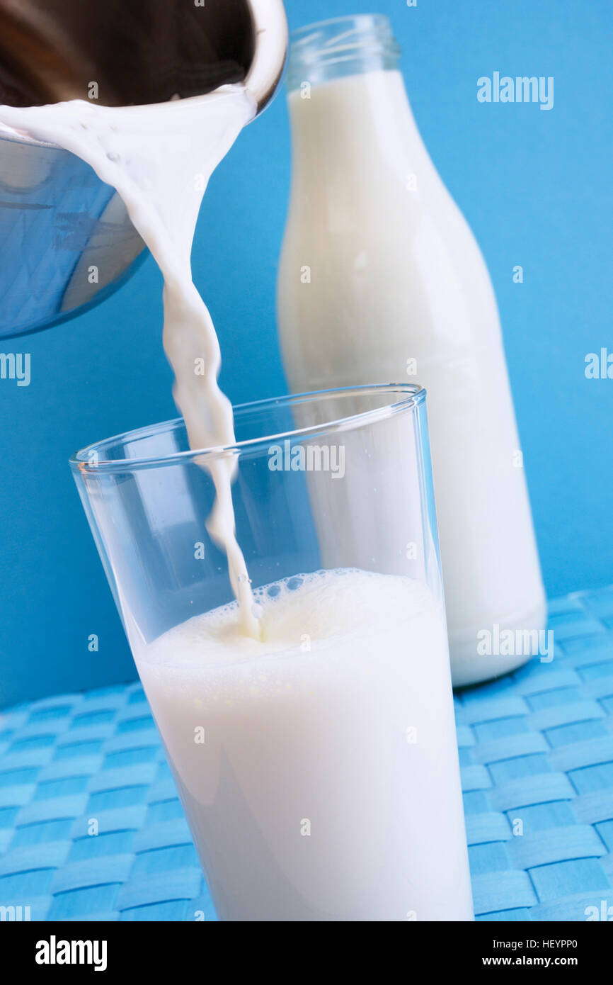 Milk being poured into a glass in front of a full milk bottle Stock ...