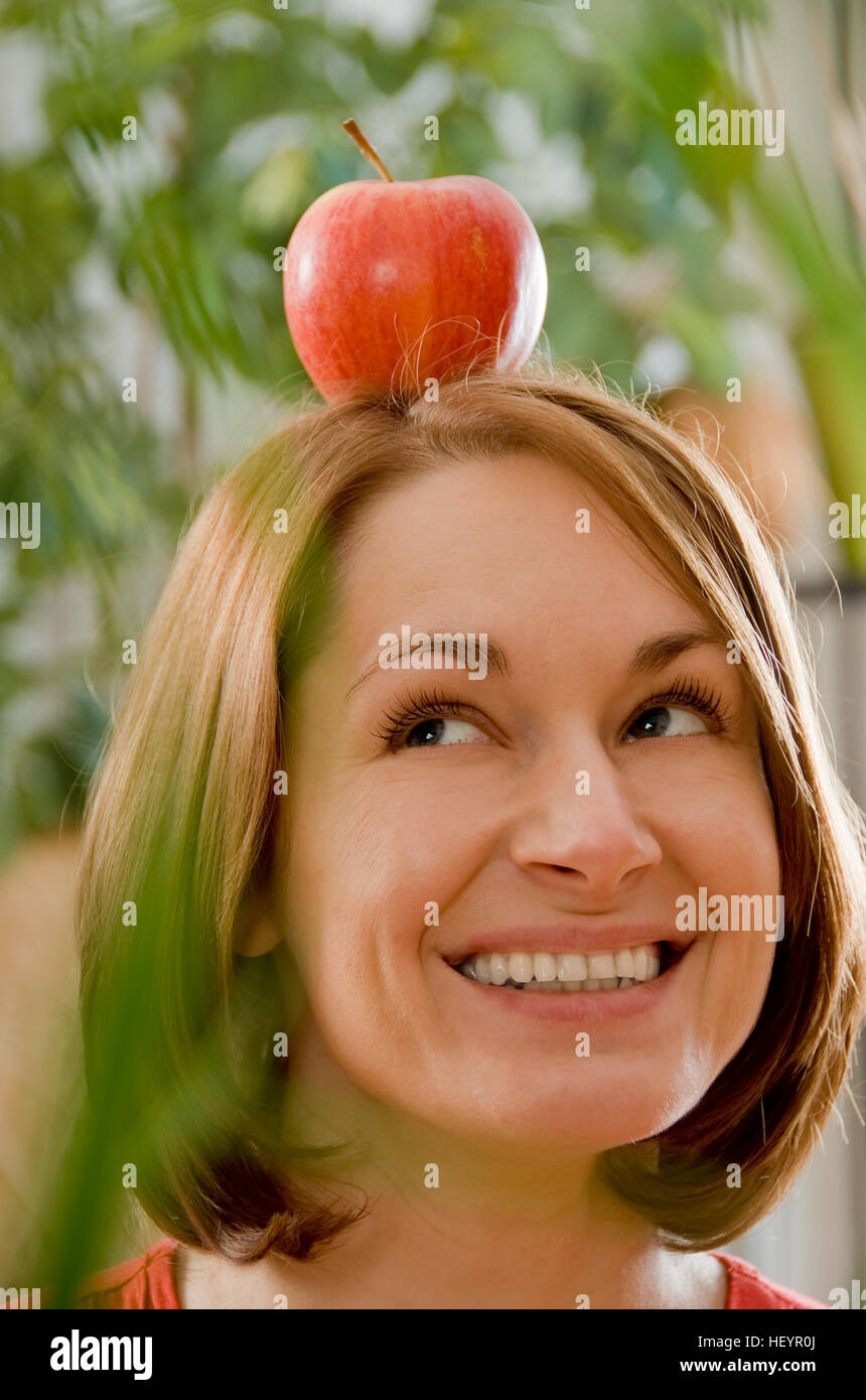 Young woman balancing an apple on her head Stock Photo - Alamy