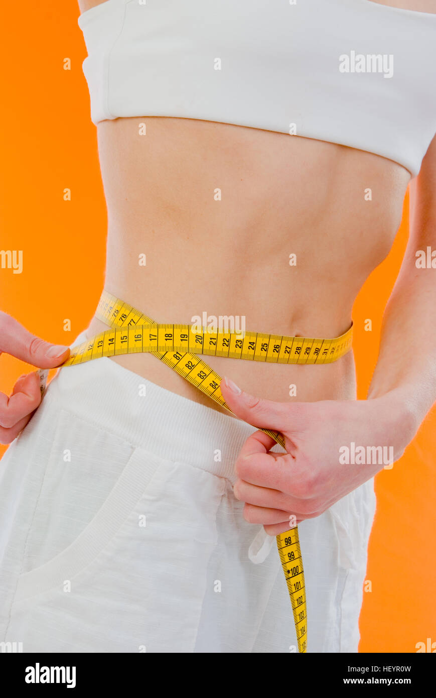 Slim young woman measuring her waist with a tape measure, waist ...