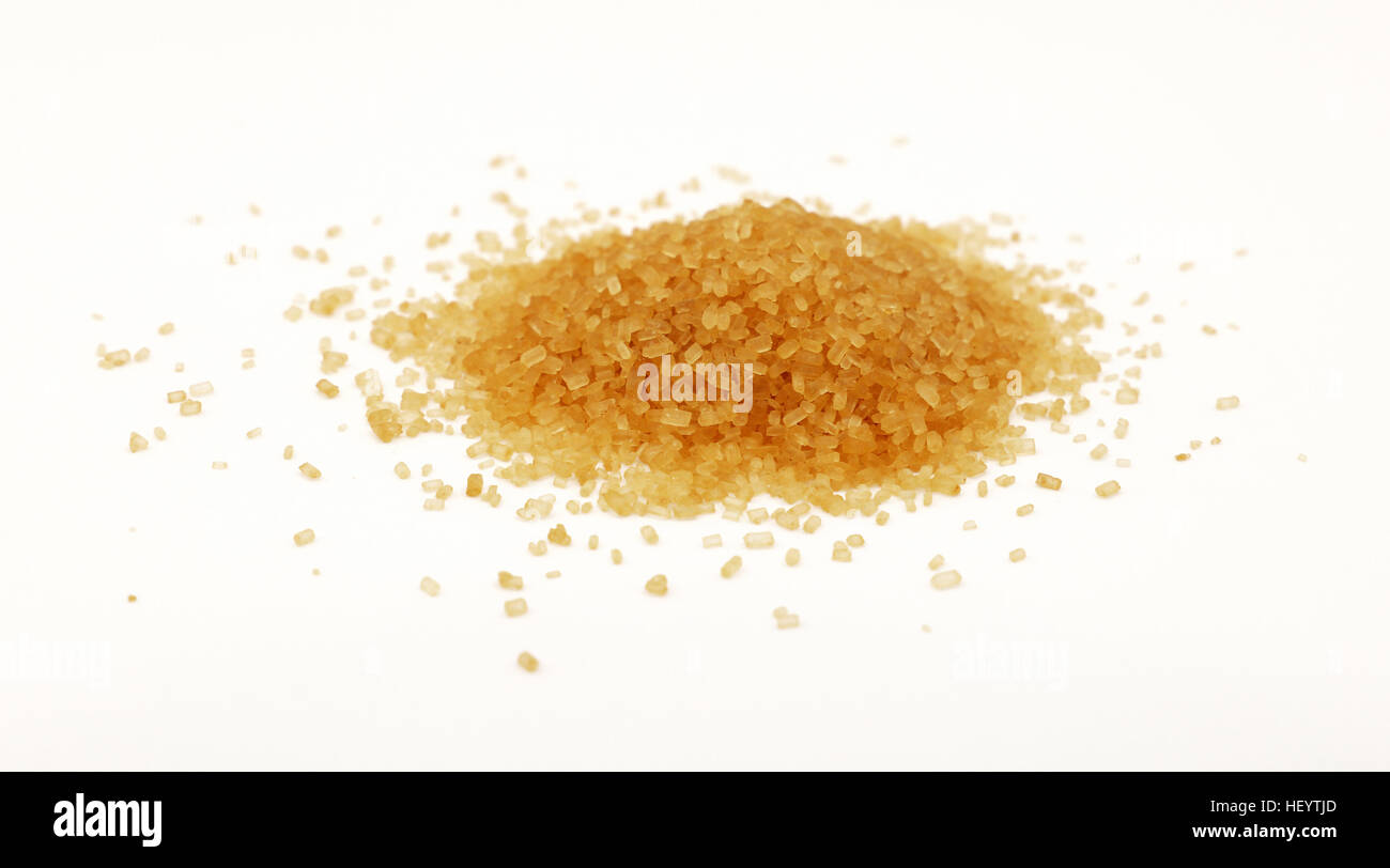 Pinch of brown cane sugar spilled around isolated on white background ...