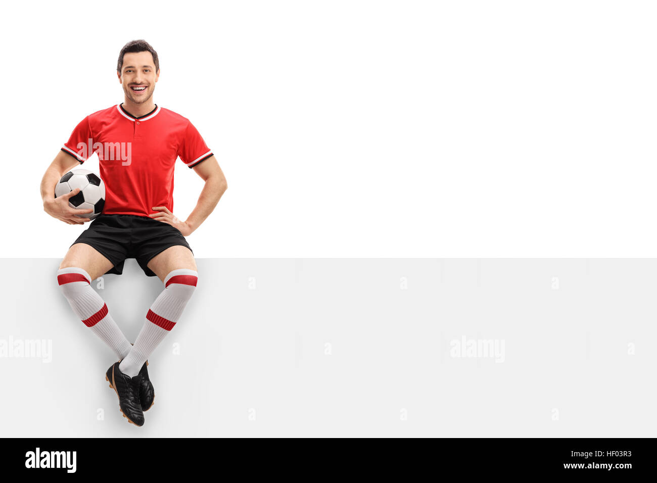 Happy football player sitting on a panel isolated on white background ...