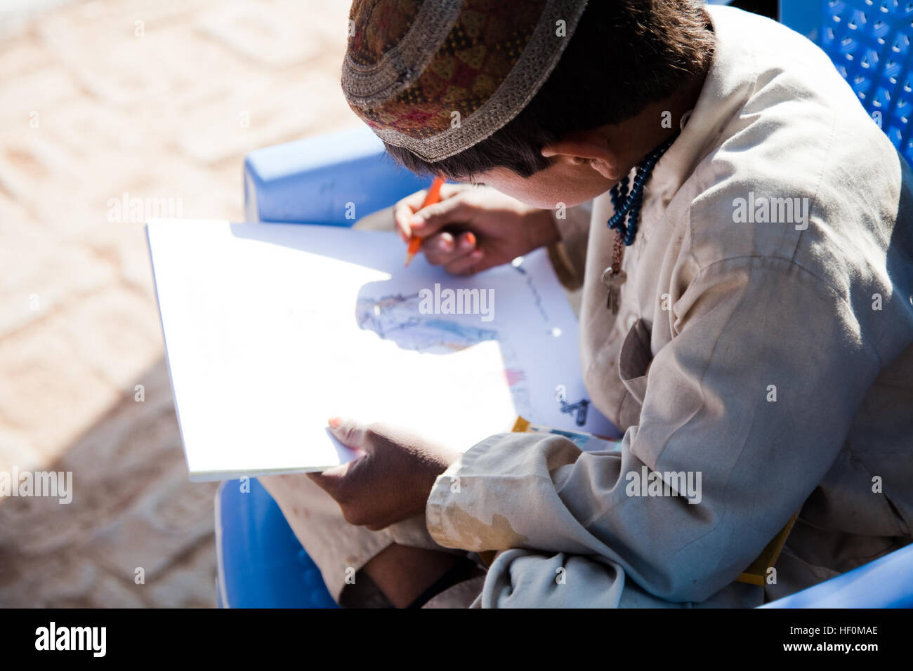 An Afghan boy draws in a coloring book at the women's center, outside ...