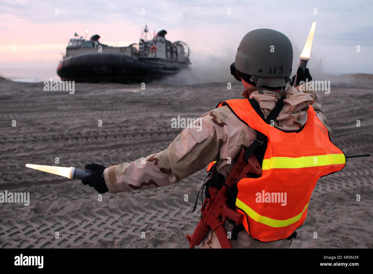 A U.S. Sailor signals for a landing craft, air cushion to leave Onslow ...