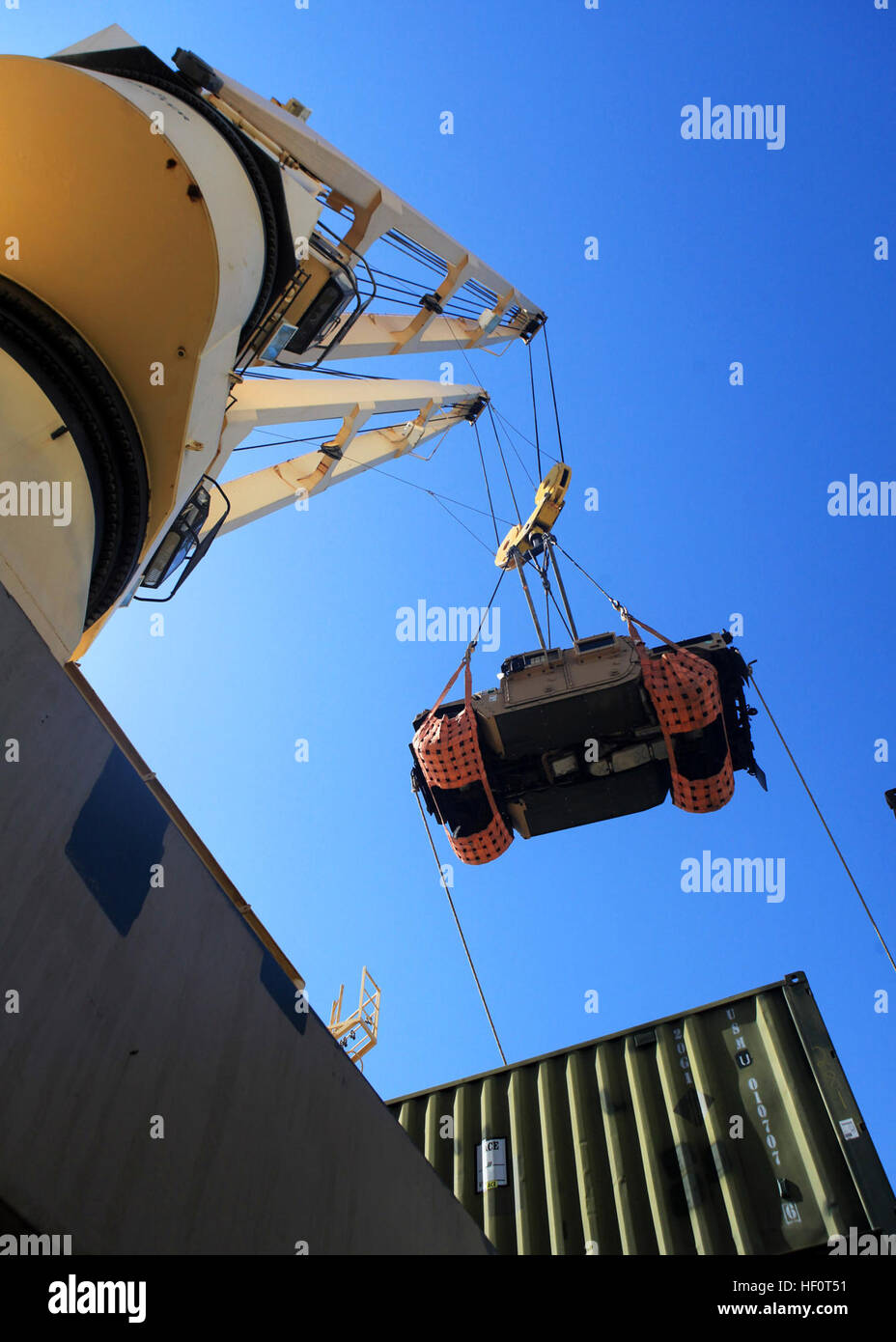 A crane lowers a Humvee from the Maritime Prepositioning Fleet ship ...
