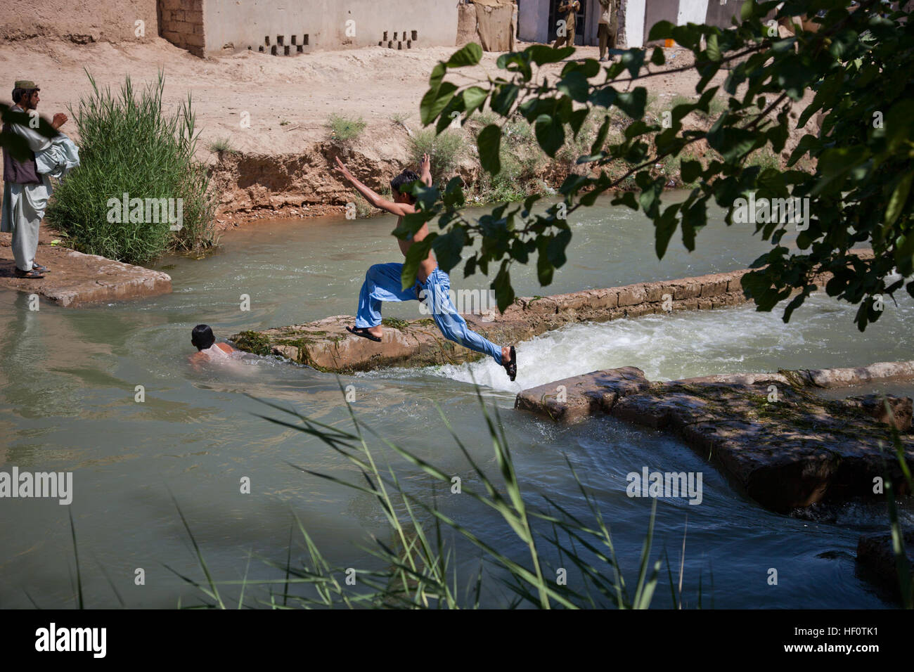 A local Afghan boy jumps into a canal outside Combat Outpost Reilly ...