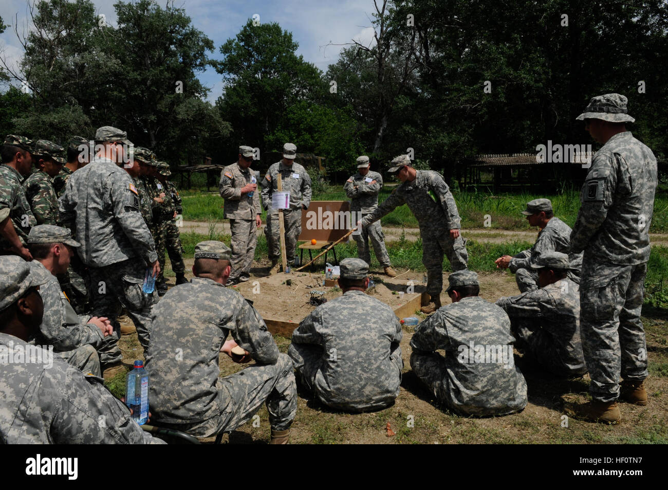 Second Lt. Corey Ryder uses a sand table to instruct soldiers from both ...