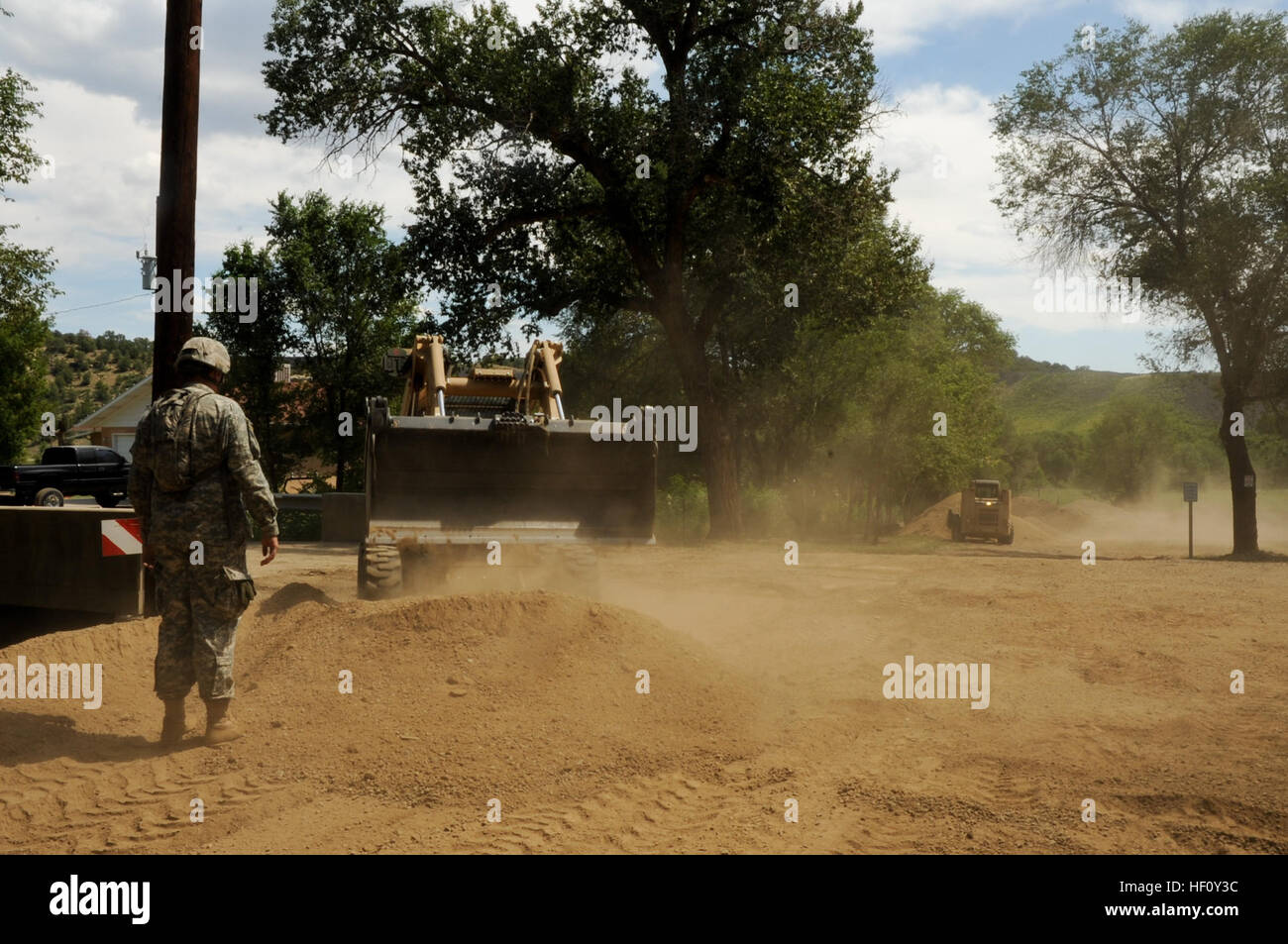 Soldiers use skid-steer loaders to remove excess material from roads in ...