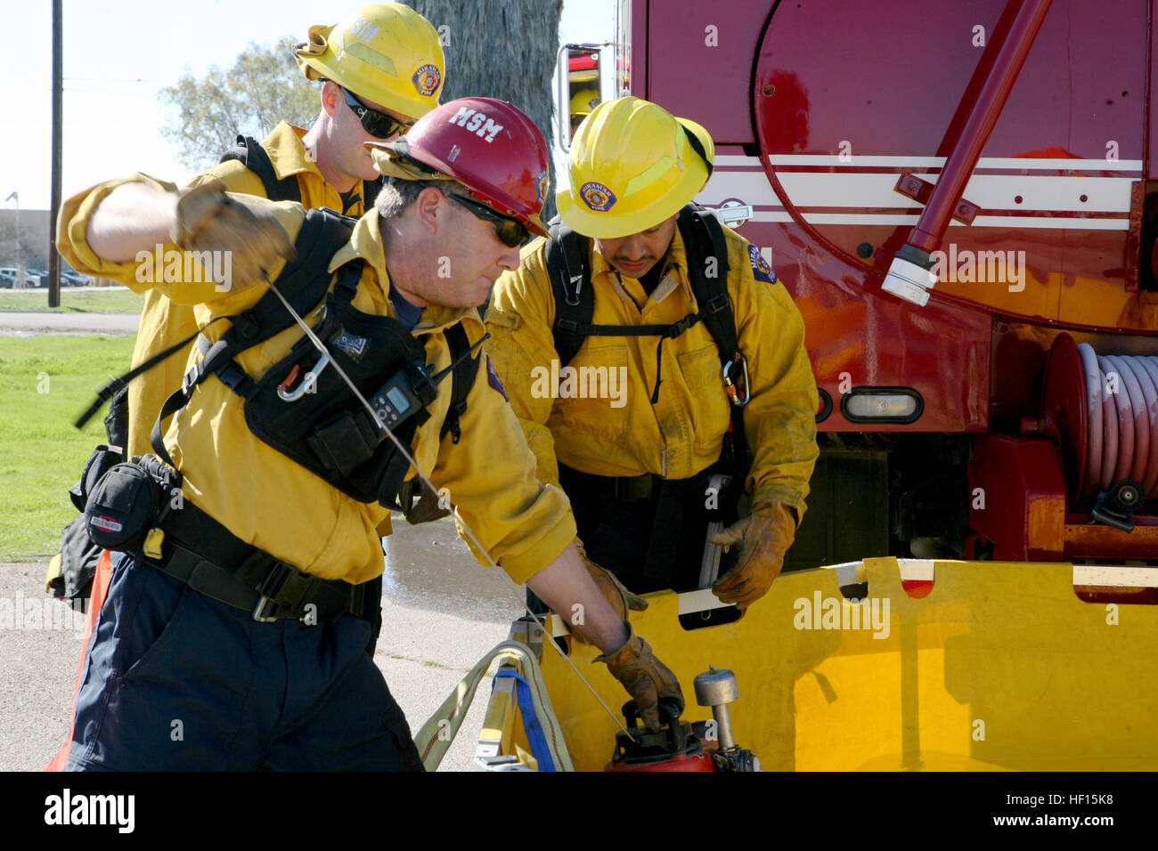 Kevin Brown (center), fire department captain, revs up a water pump ...