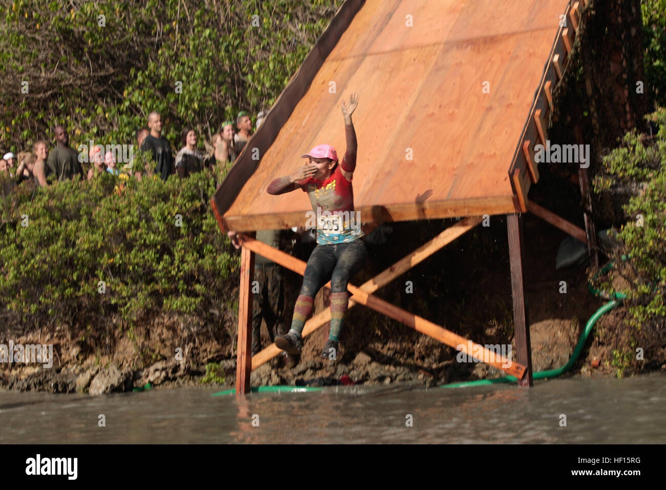 At one of the many obstacles, a competitor slides down into a pool of ...