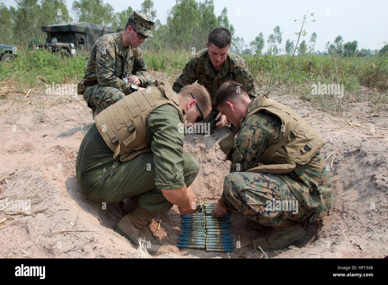 U.S. Marines place 20mm rounds in a hole at a demolition range to ...