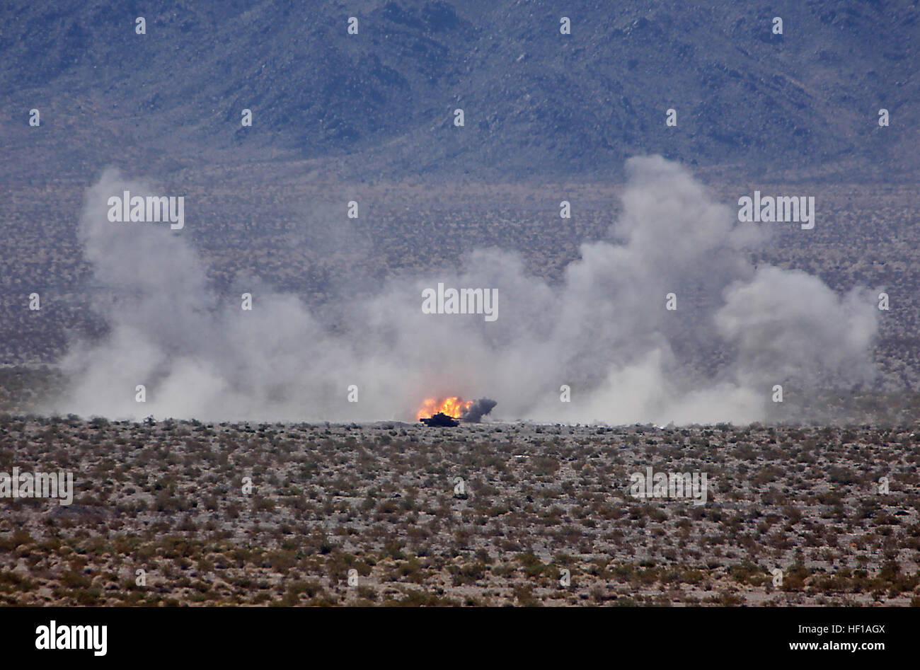 An artillery round explodes near a rusted tank during call-for-fire ...
