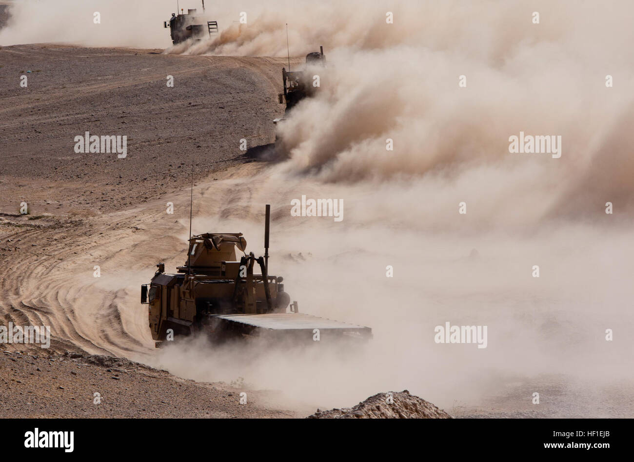 Clouds of dust fill the air as a convoy of vehicles with Combat ...