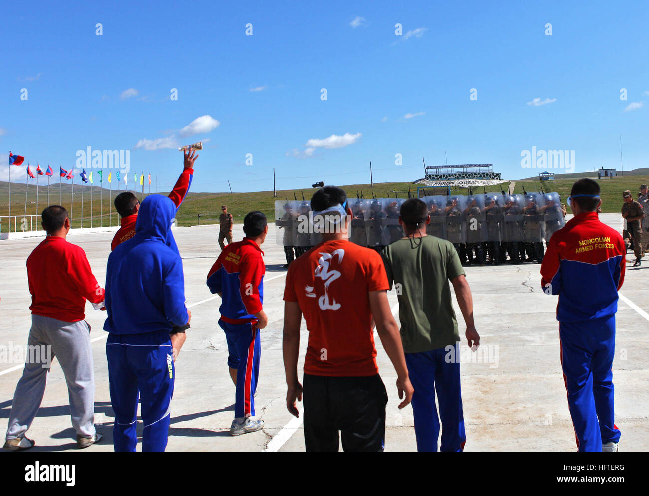 Role players hurl rock-filled water bottles as service members with the ...