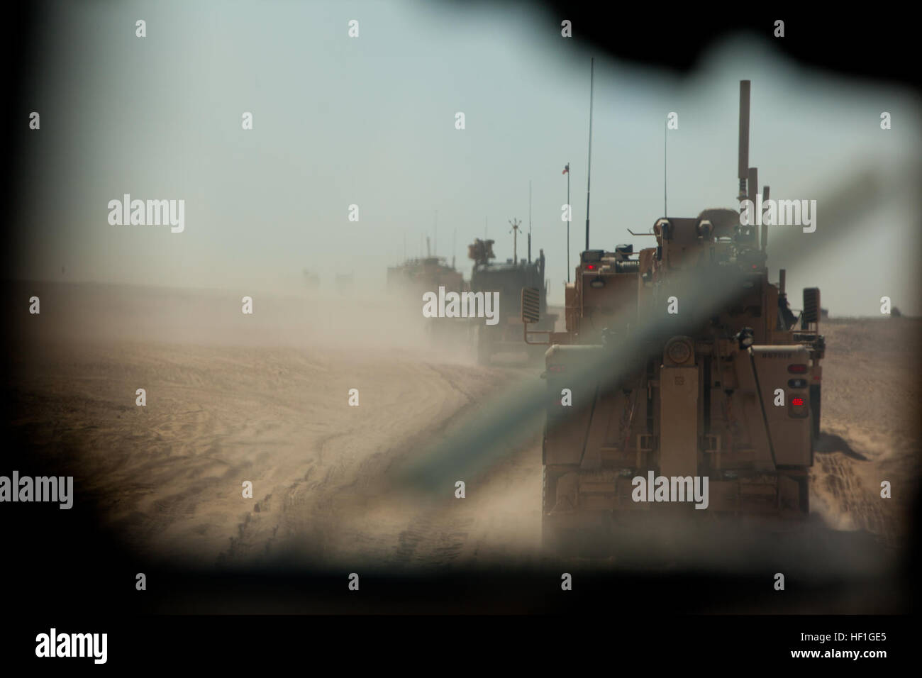 A line of vehicles drive along a desert road in Helmand province ...