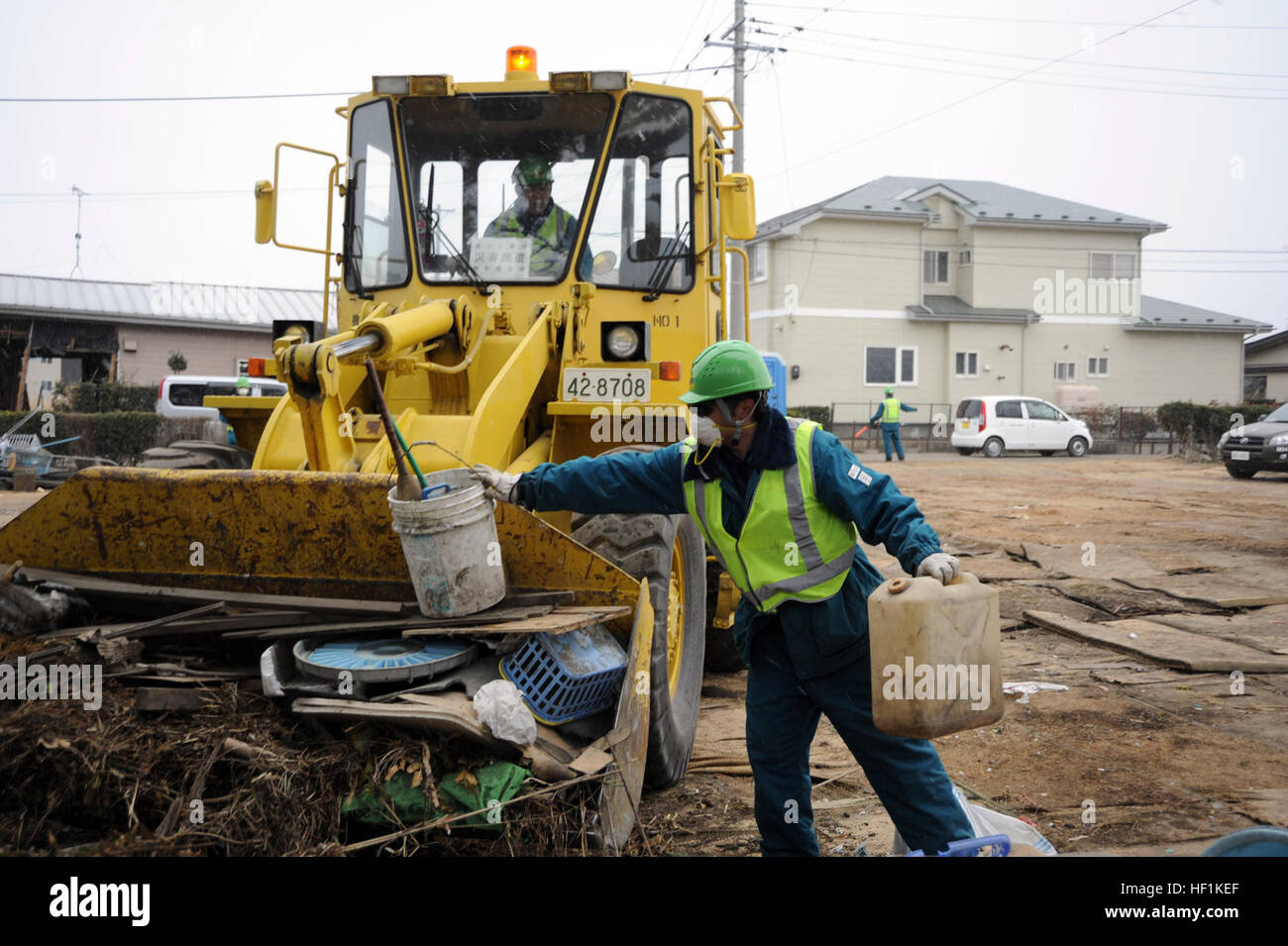 A Japan Maritime Self-Defense Force sailor loads debris in the bucket ...