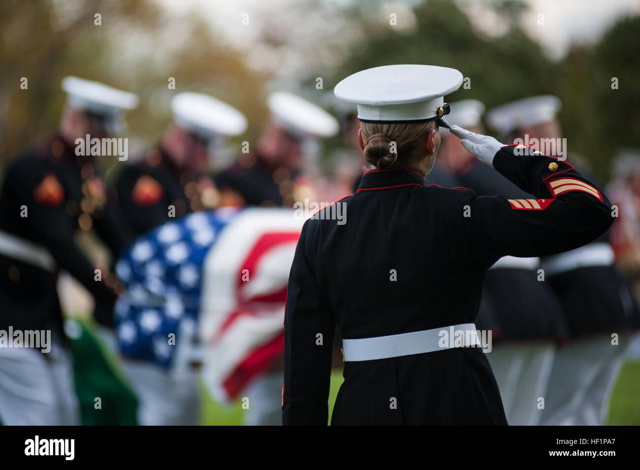U.S. Marine Corps Sgt. Katie Maynard salutes as a casket is lowered ...