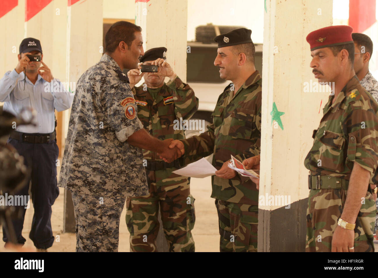 Iraqi Police (IP) Lt. Col. Aziz (right) shakes a graduates hand at the ...