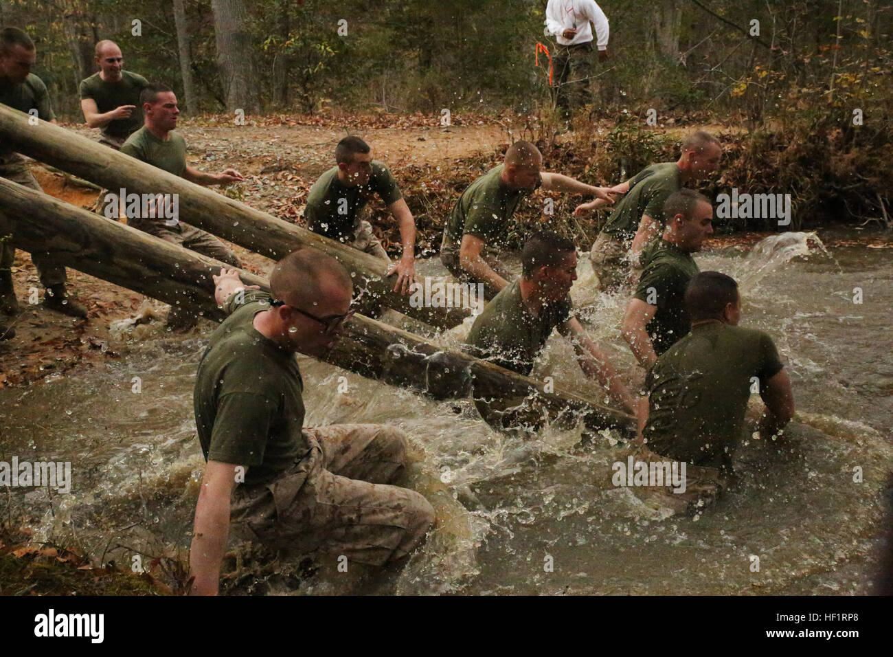 Marine candidates jump into water while transporting logs during a ...