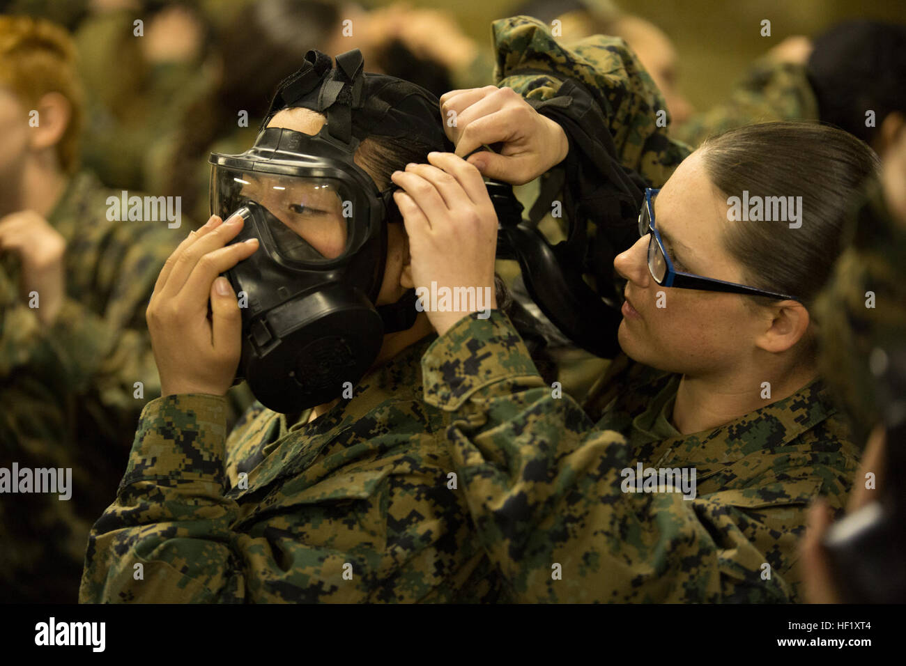 Rct. Michelle Kingsbury tightens a gas mask worn by Rct. Audrey Guevara ...