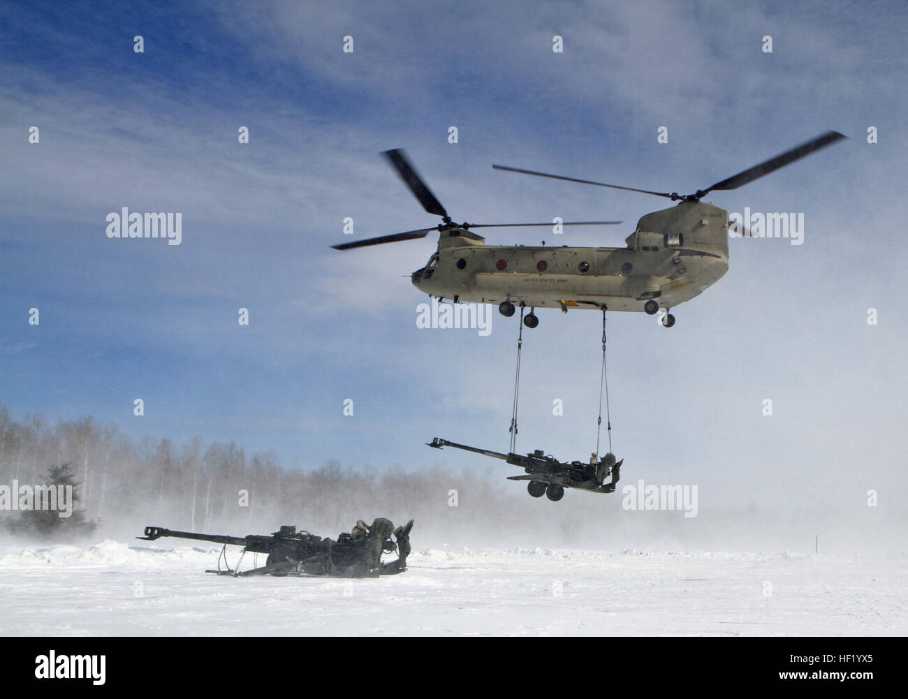 An M-177 155mm howitzer is transported by a CH-47 Chinook during cold weather sling load ...
