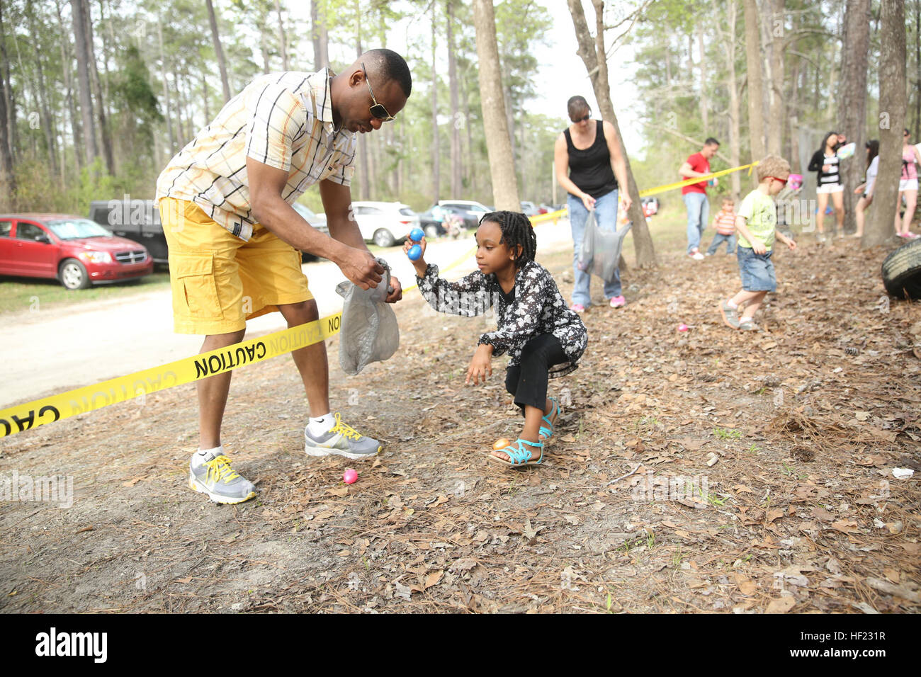Navy Lt. Kyron Bell assists his daughter during an Easter egg hunt at ...