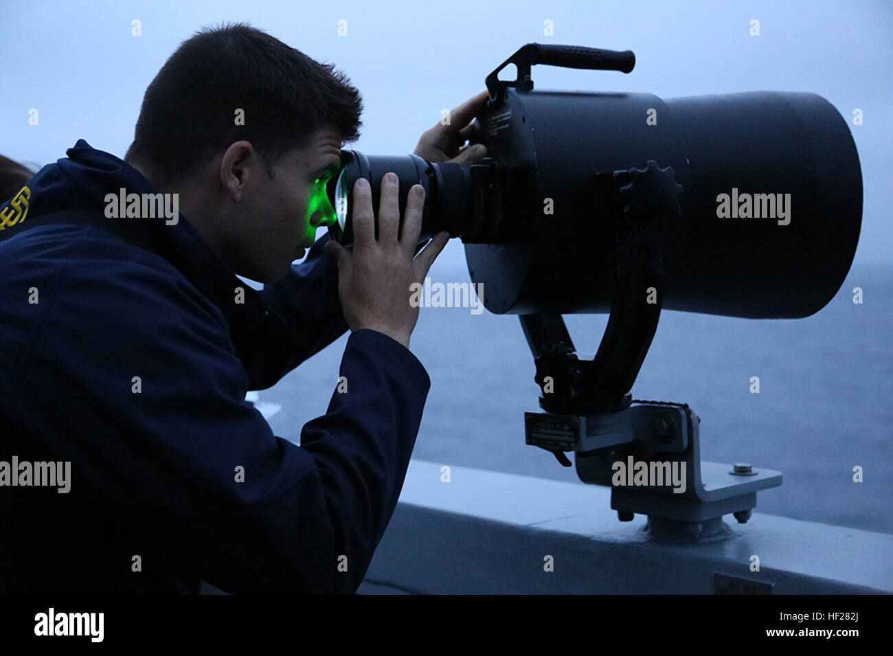 A sailor with the USS San Diego scans the water through an AN/PVS-8 ...