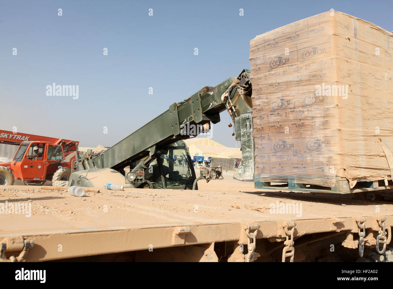 A fork lift operator unloads a pallet of water from a Medium Tactical ...