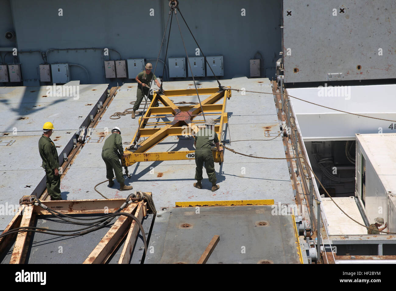 Marines guide a boom after unloading a mobile maintenance facility ...