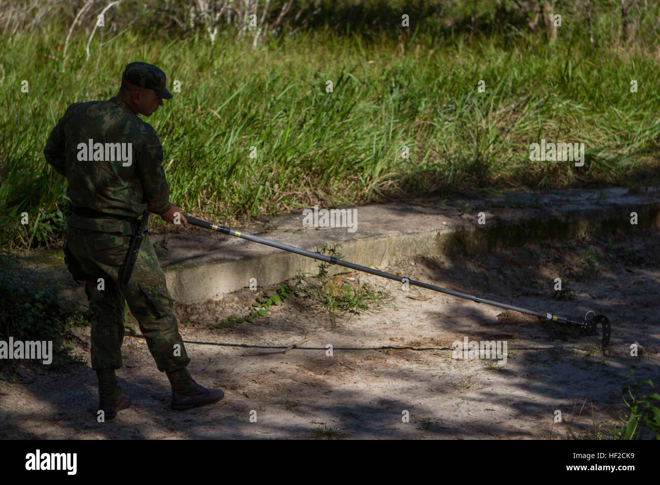 A Brazilian special forces Marine utilizes a holly stick to inspect the ...