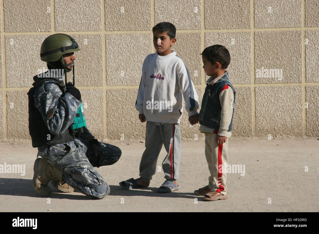 An Iraqi police officer talks to children as U.S. Marines (not shown ...