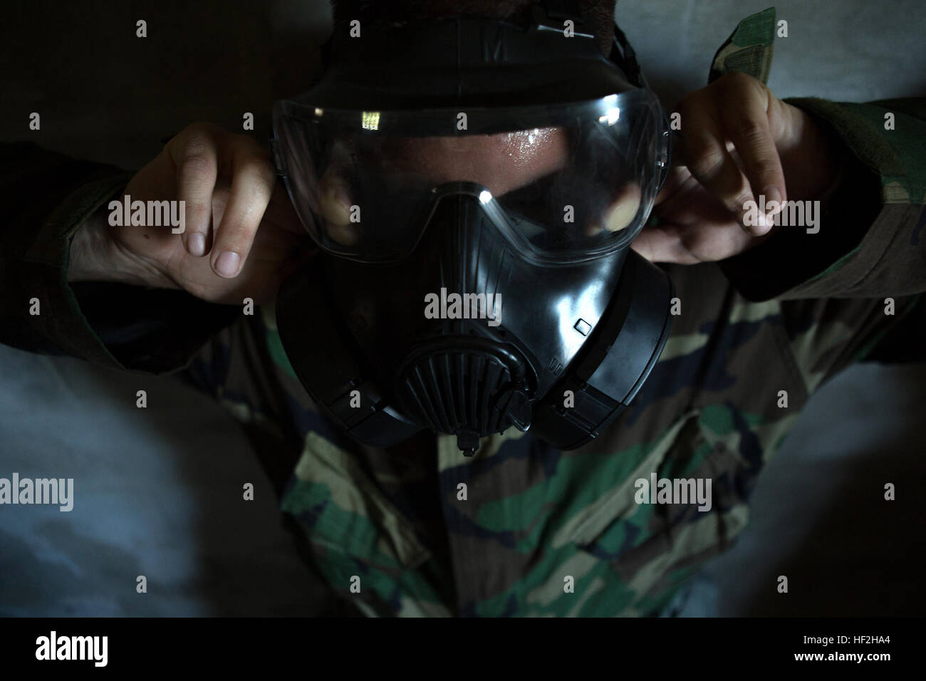 A Marine breaks the seal of his M50 gas mask to saturate the inside of ...