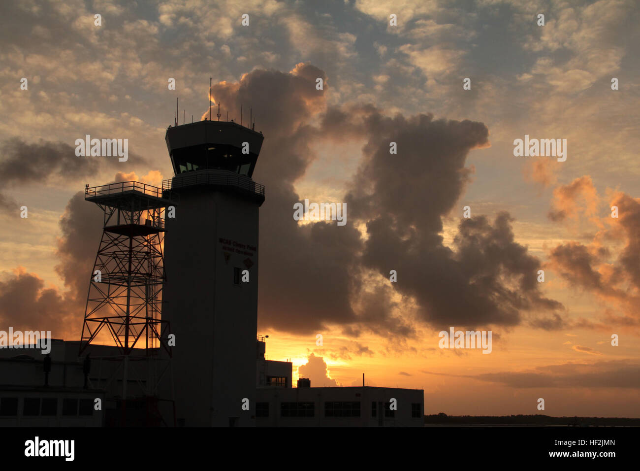 The air traffic control tower is silhouetted by the rising sun over ...