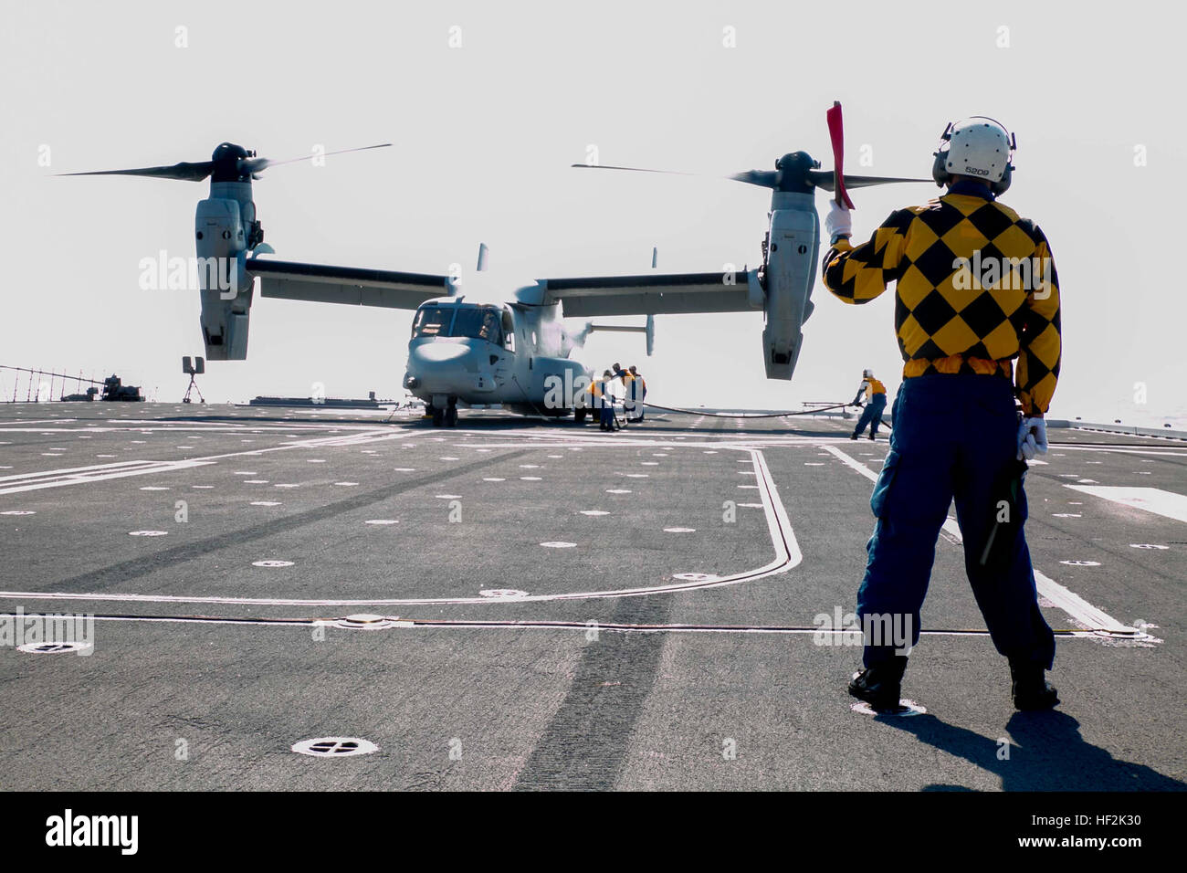 A Japan Maritime Self-Defense Force service member signals an MV-22B ...