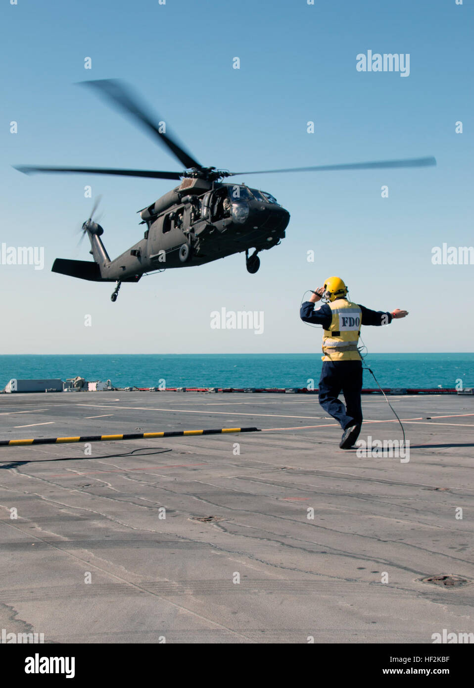 A flight deck officer with the British Royal Navy directs the UH-60 ...