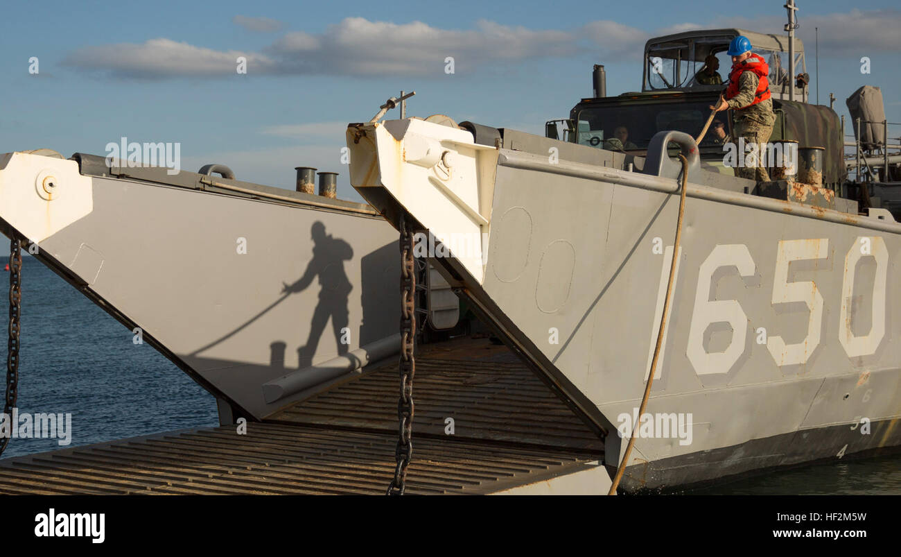 A U.S. sailor draws in a rope on landing craft utility 1650 prior to ...