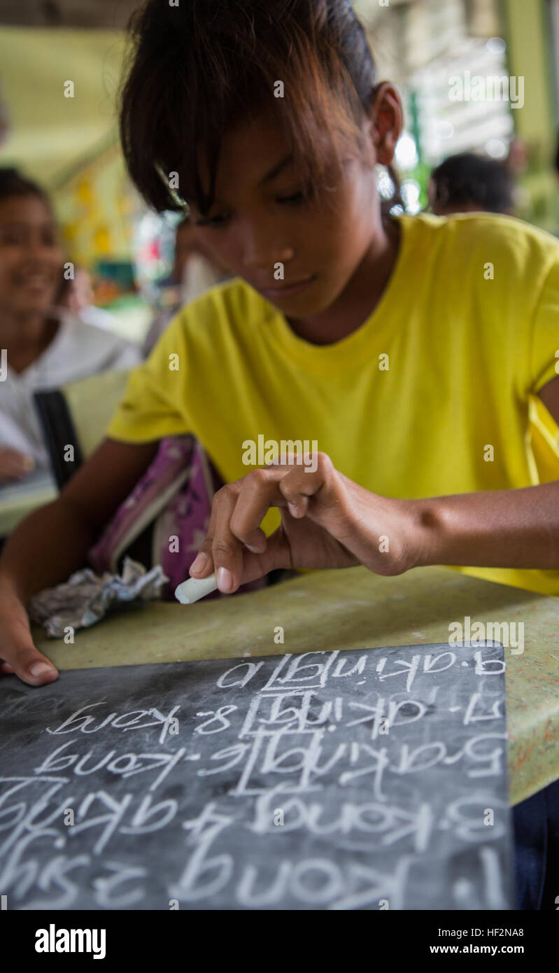 A young Filipino girl writes on a chalkboard during class at the ...